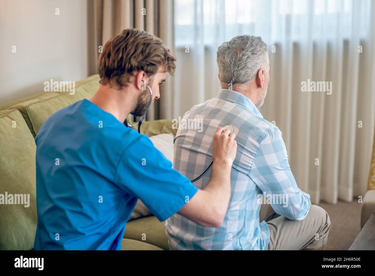 Experienced doctor using a stethoscope during the medical check-up ...