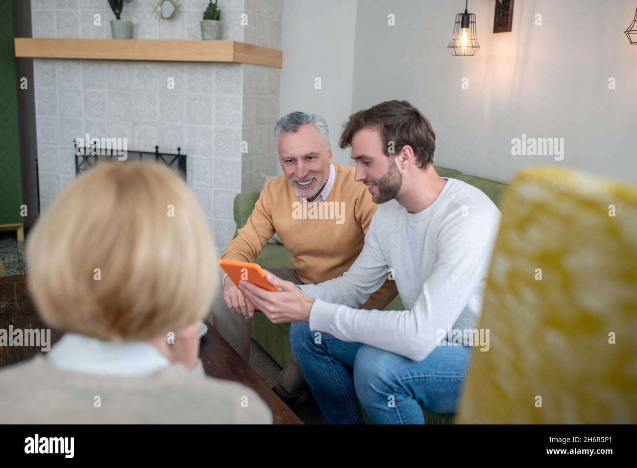 Son visiting parents and showing new photos to them Stock Photo - Alamy