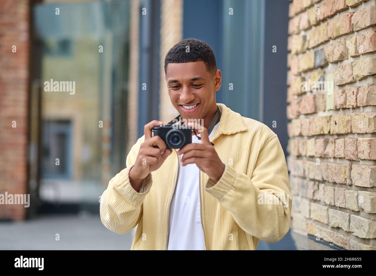Positive photographer with camera in hands looking happy Stock Photo ...