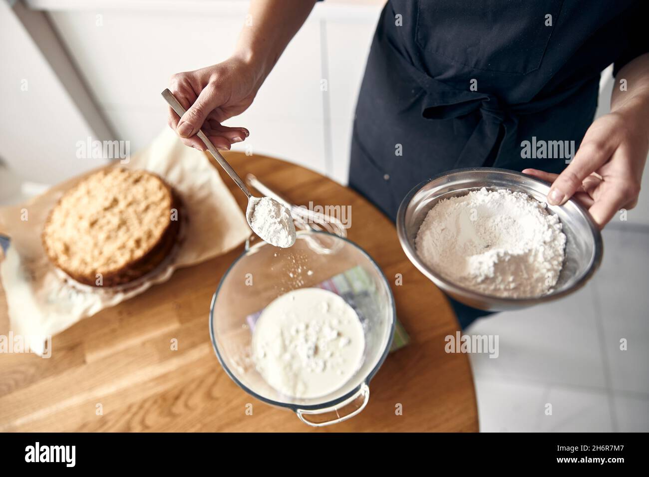 young professional female cook is preparing tasty cake at her light ...