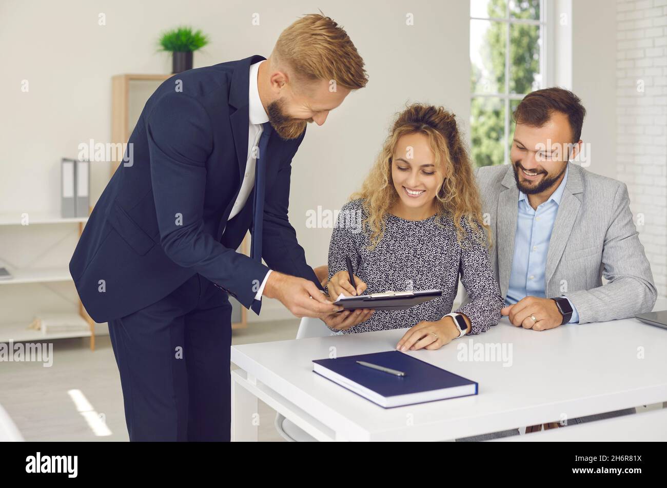 Happy couple buying house, meeting with their real estate agent and ...