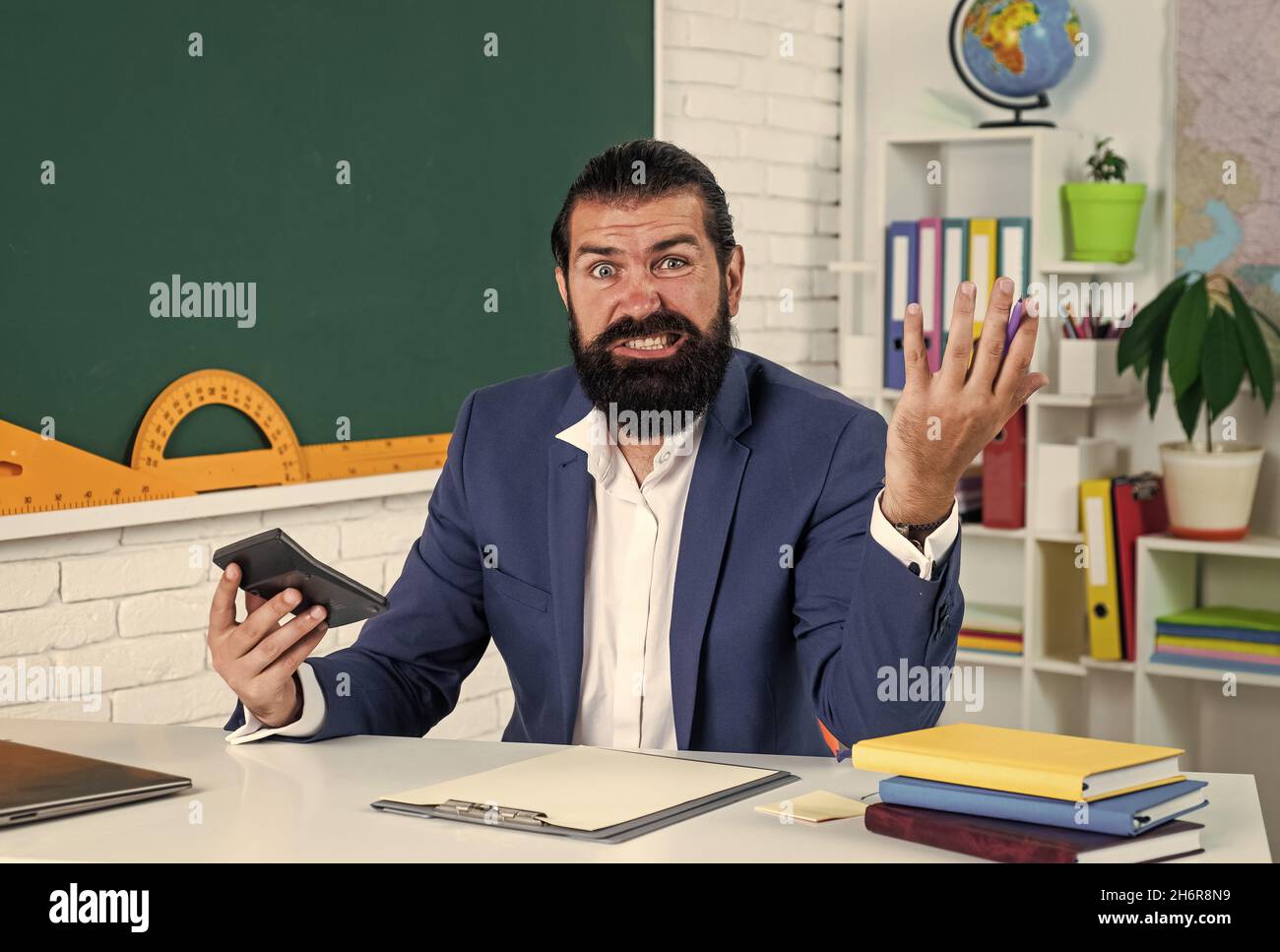 confused guy with beard calculating on calculator in school math lesson ...