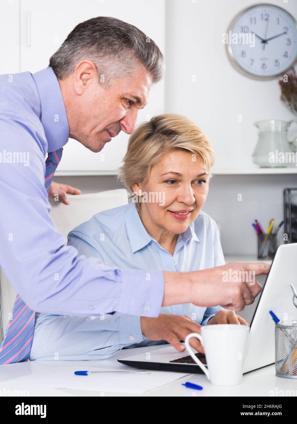 Mature man helping his colleague Stock Photo - Alamy
