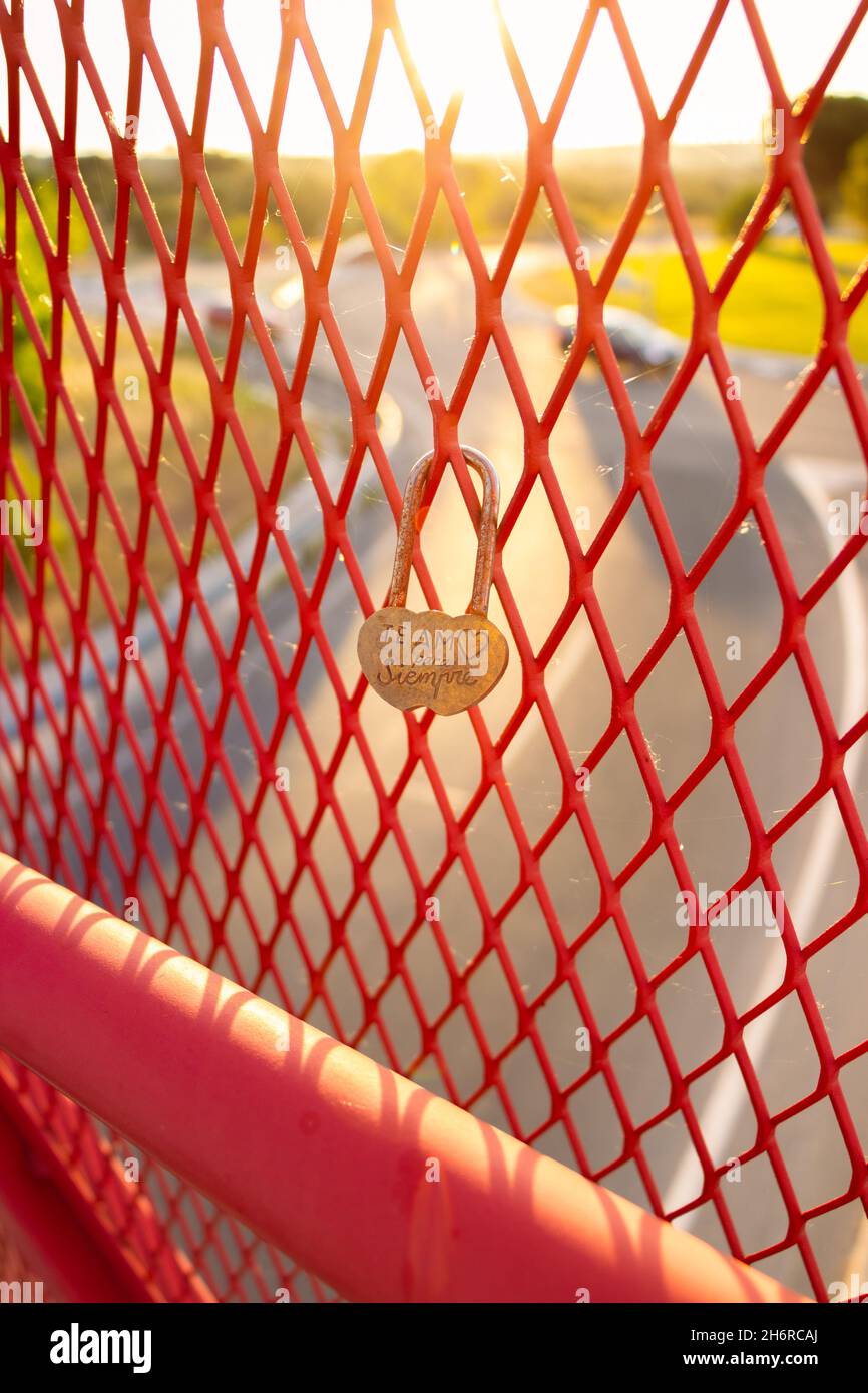 Closeup of padlock with ""TE AMO" phrase hanging on the red mesh grid ...