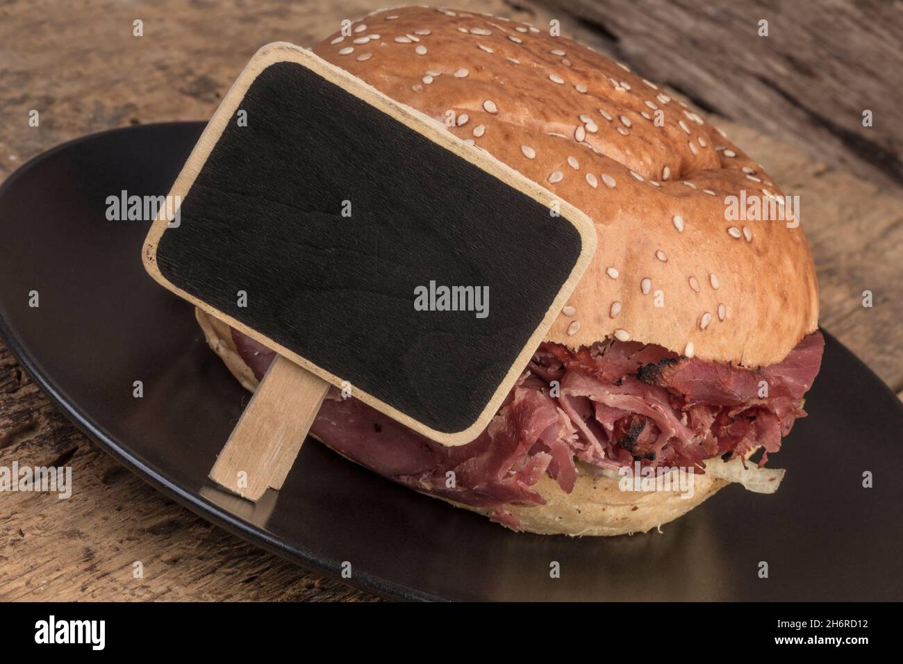 A delicious roast beef burger and an empty chalkboard on wooden table ...