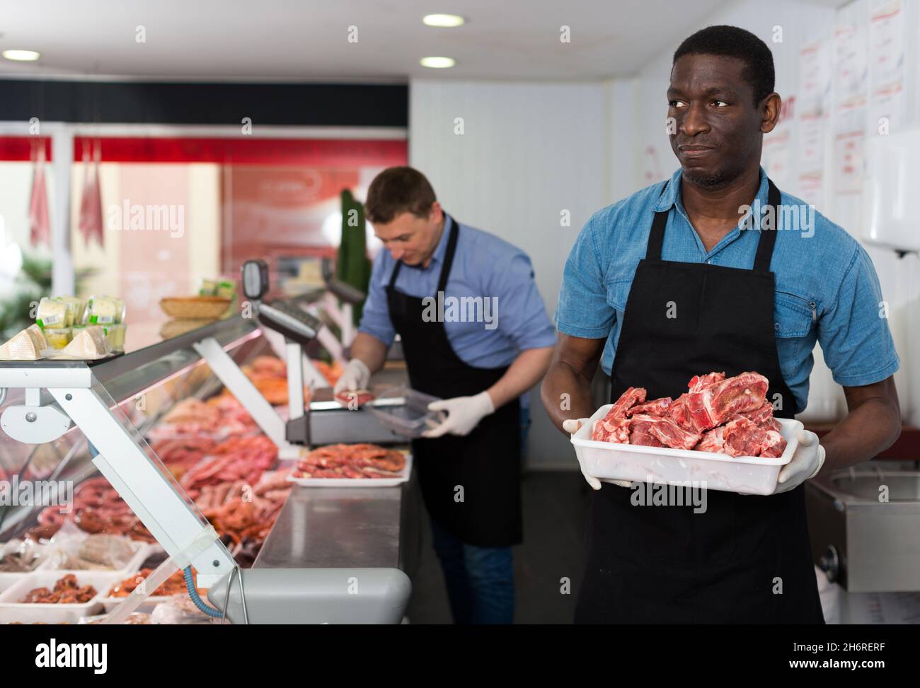 Butchers working behind counter Stock Photo - Alamy