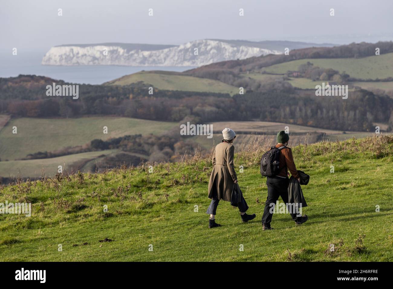A couple walking across Mottistone Downs overlooking the chalk cliff ...