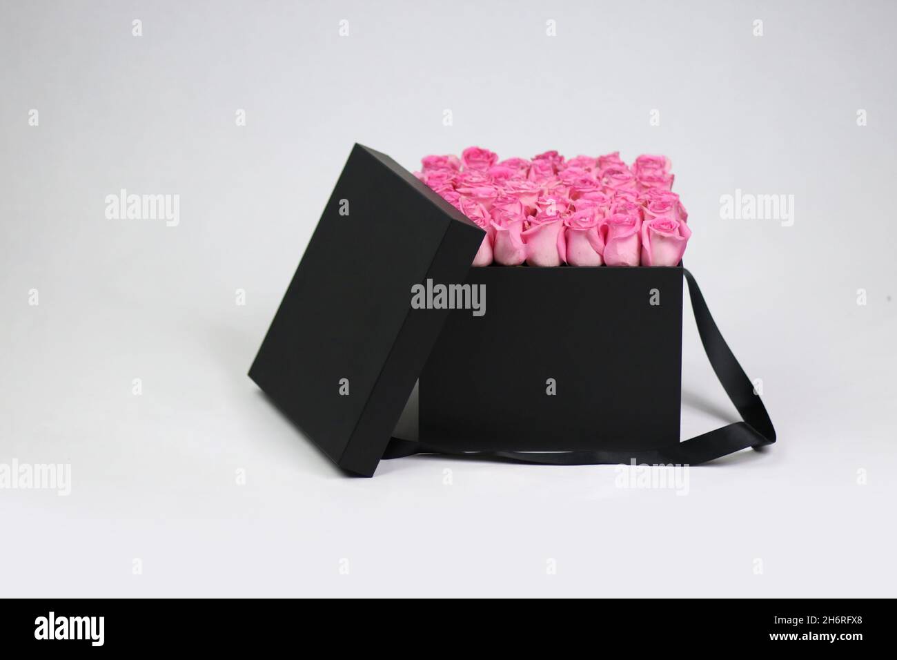 Black square gift flower box with pink roses inside. Stylish flower ...