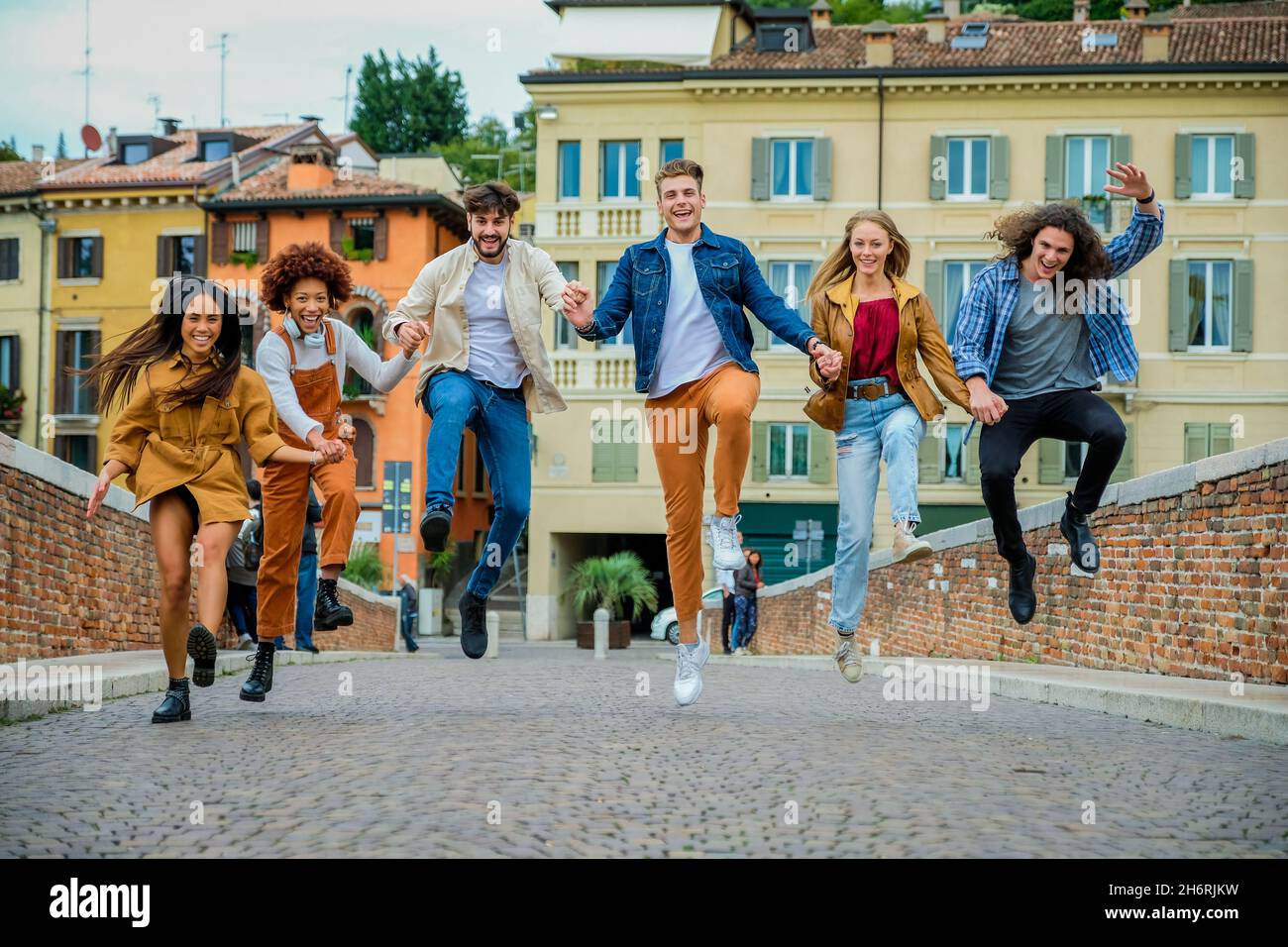 Multiethnic group of crazy young people having fun walking and jumping ...
