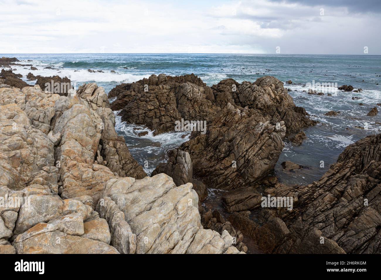 Rocky jagged coastline, eroded sandstone rock, view out to the ocean ...