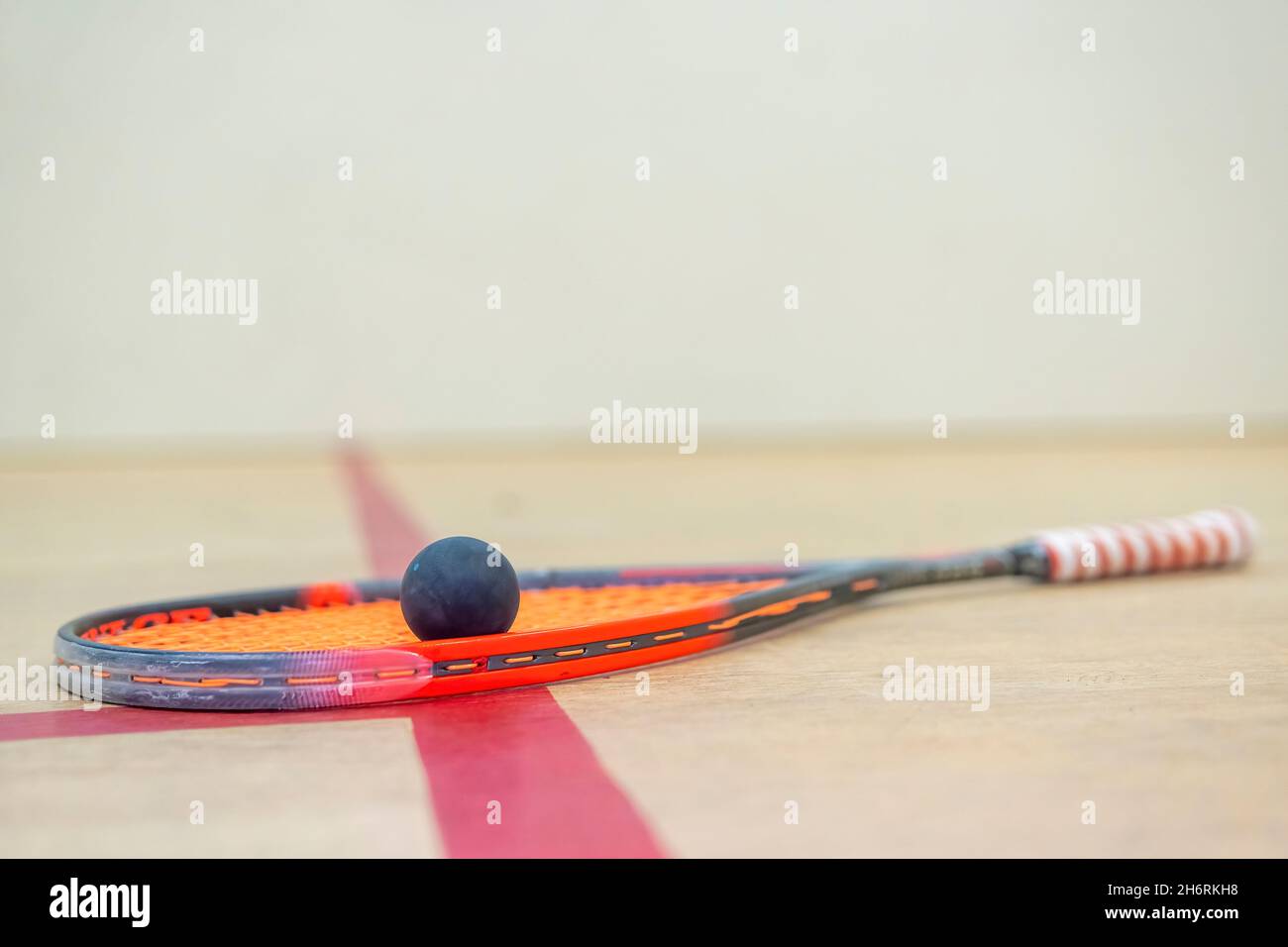 the squash racket and ball lie on the wooden floor between the lines ...
