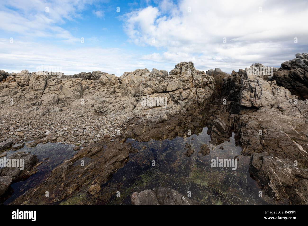 Rocky jagged coastline, eroded sandstone rock, view out to the ocean ...