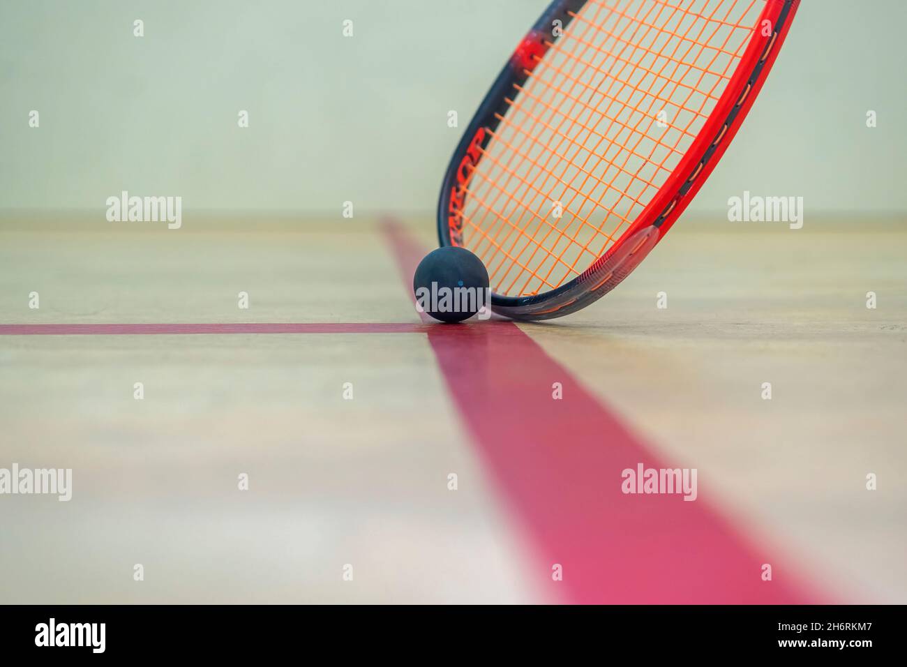 the squash racket and ball lie on the wooden floor between the lines ...