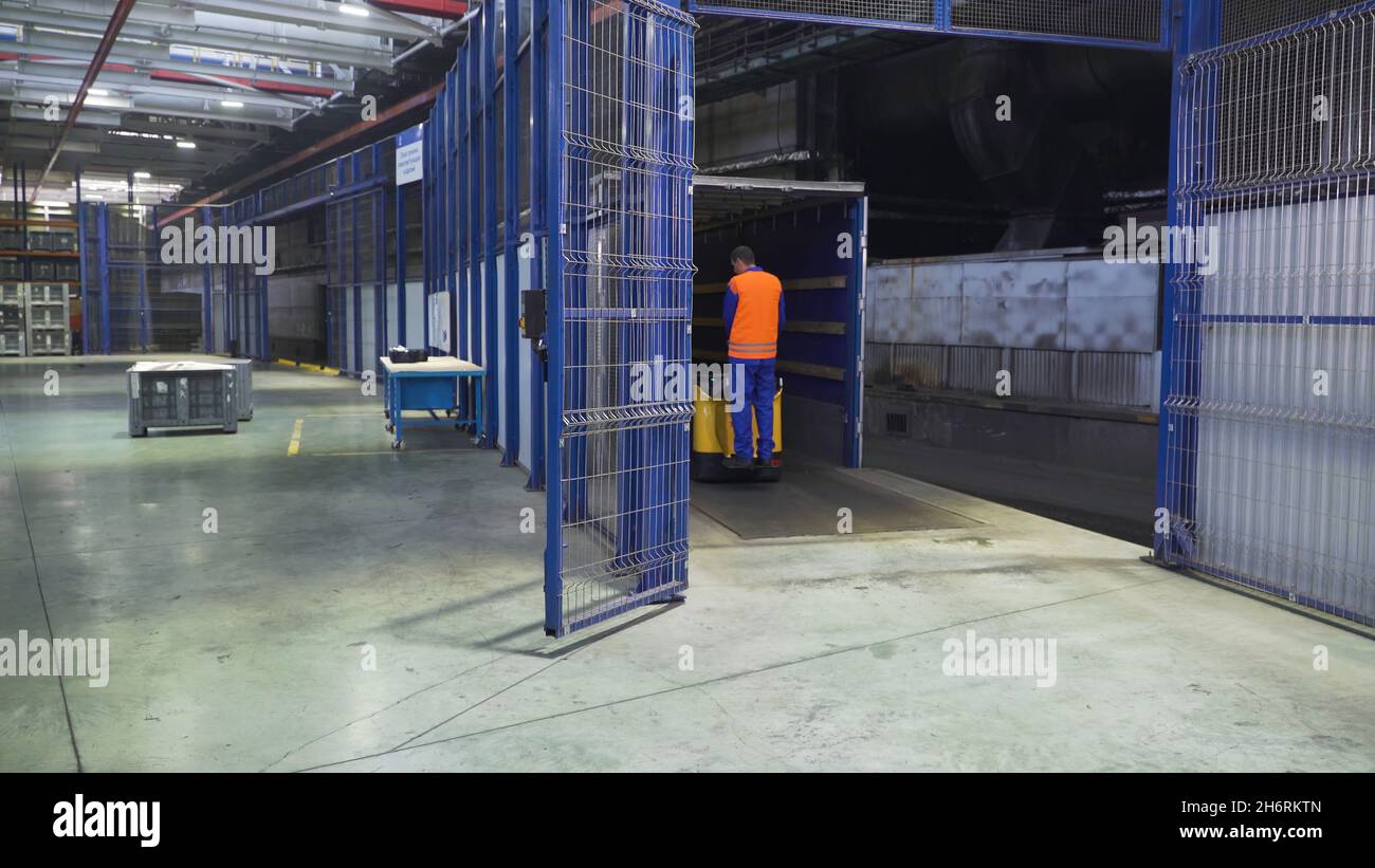 Worker on loader transports boxes in warehous. Scene. Worker standing ...