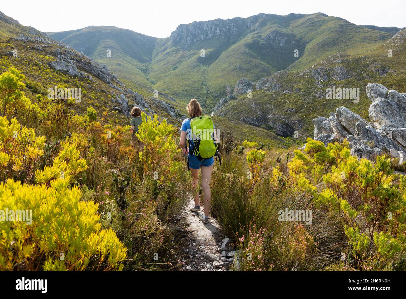 A teenage girl walking along a path in the mountains with a backpack ...
