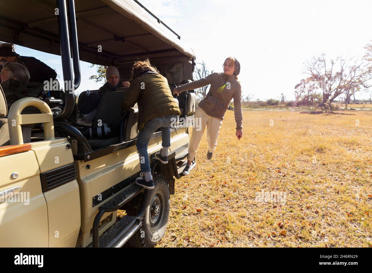 A teenage girl and a young boy climbing into a safari jeep Stock Photo ...