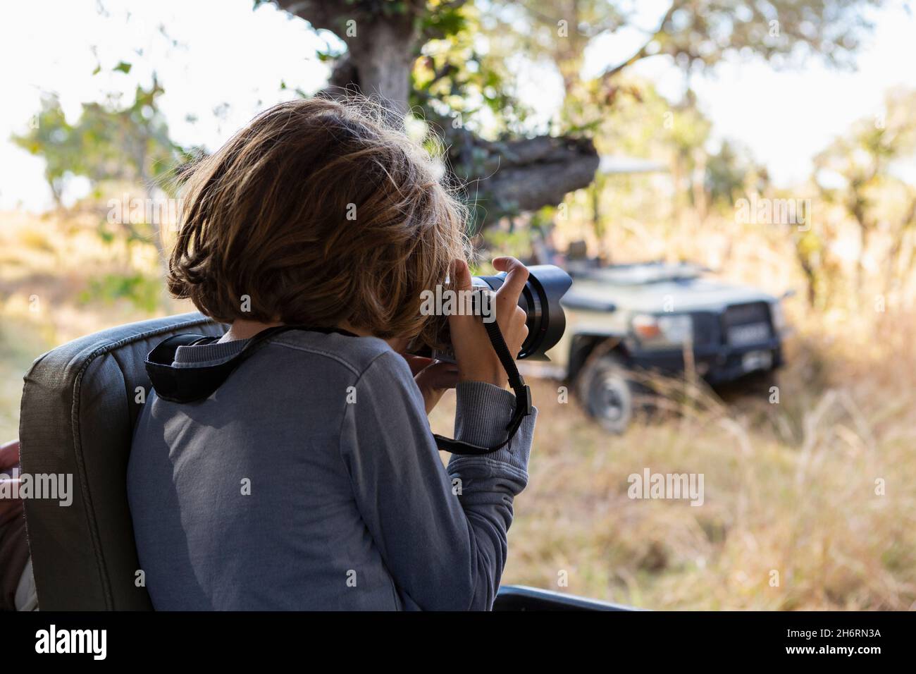 young boy using a large camera during a jeep drive on safari Stock ...