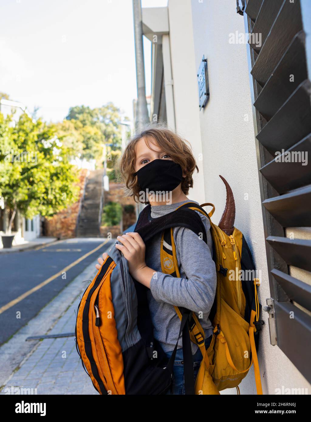A boy carrying a backpack with a black facemask on a street Stock Photo ...