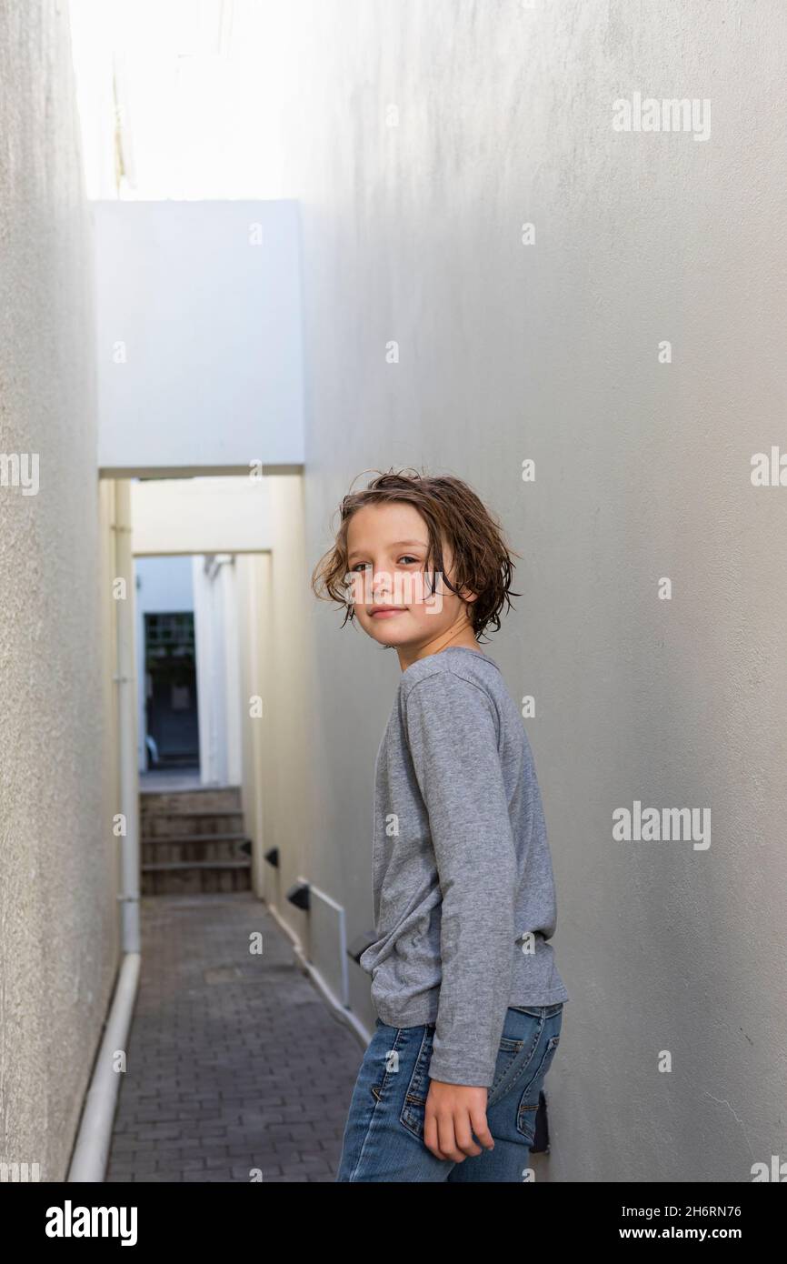 Portrait of young boy in alleyway, turning around to look at the camera ...
