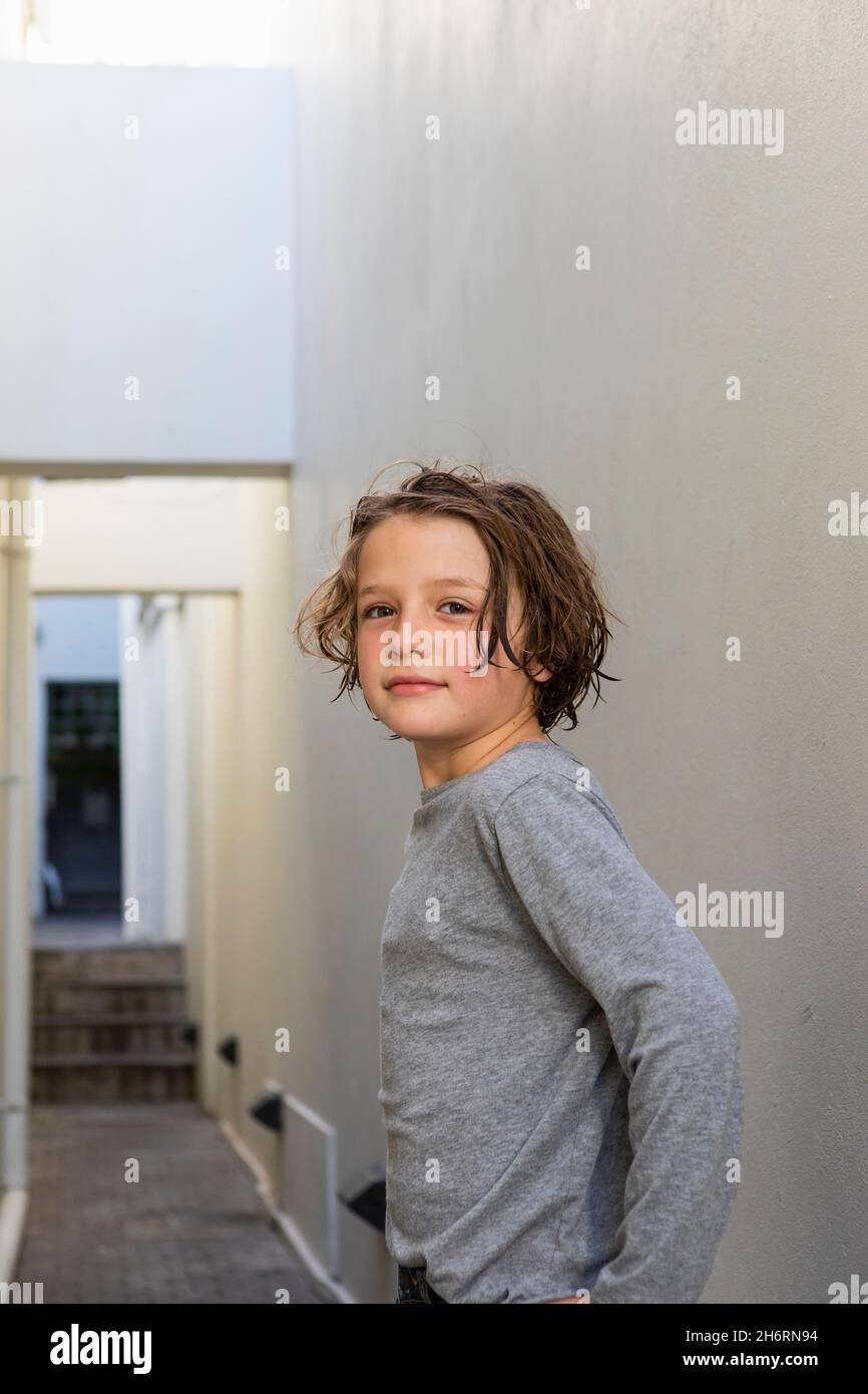 Portrait of young boy in a narrow alleyway, turning to look at the ...