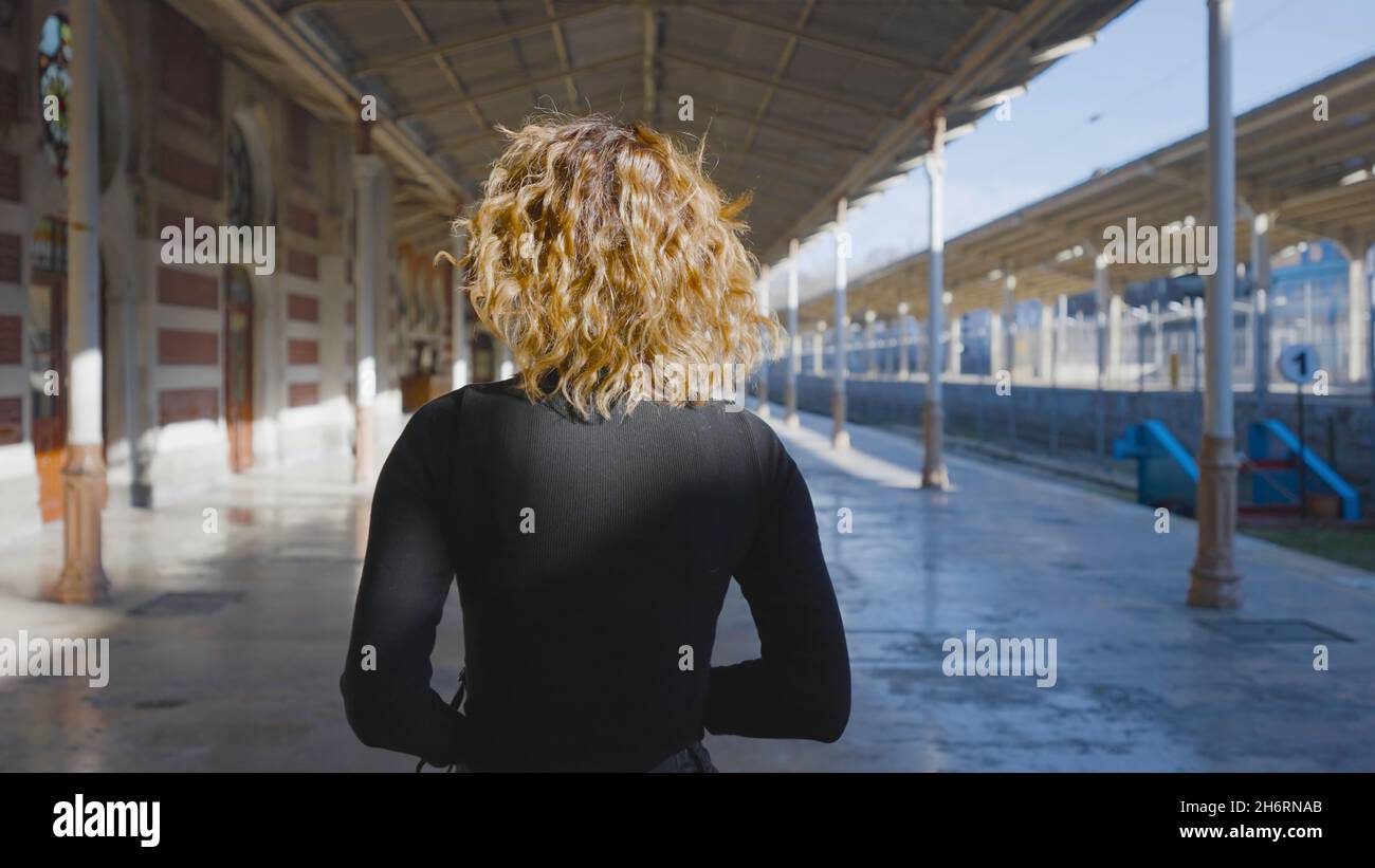 Beautiful woman walking through station. Action. Rear view of ...