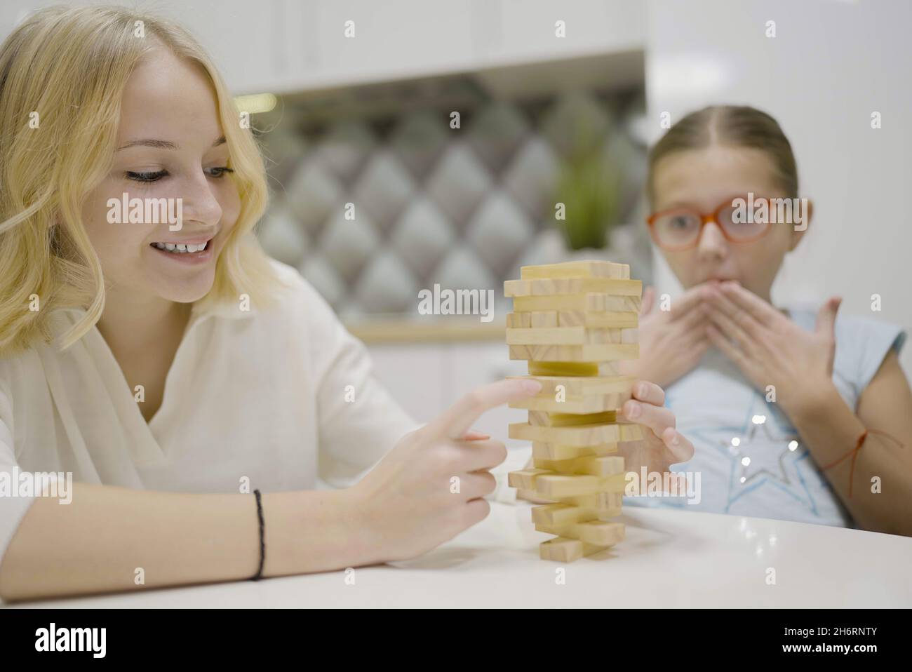 two girls have fun playing Jenga together - board game to remove wooden ...