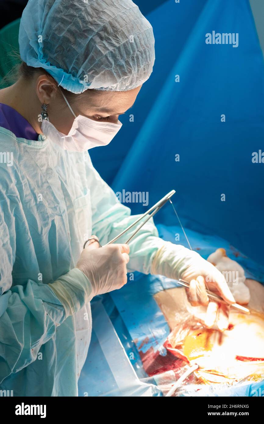 The female surgeon completes the surgery and sutures the patient's skin ...