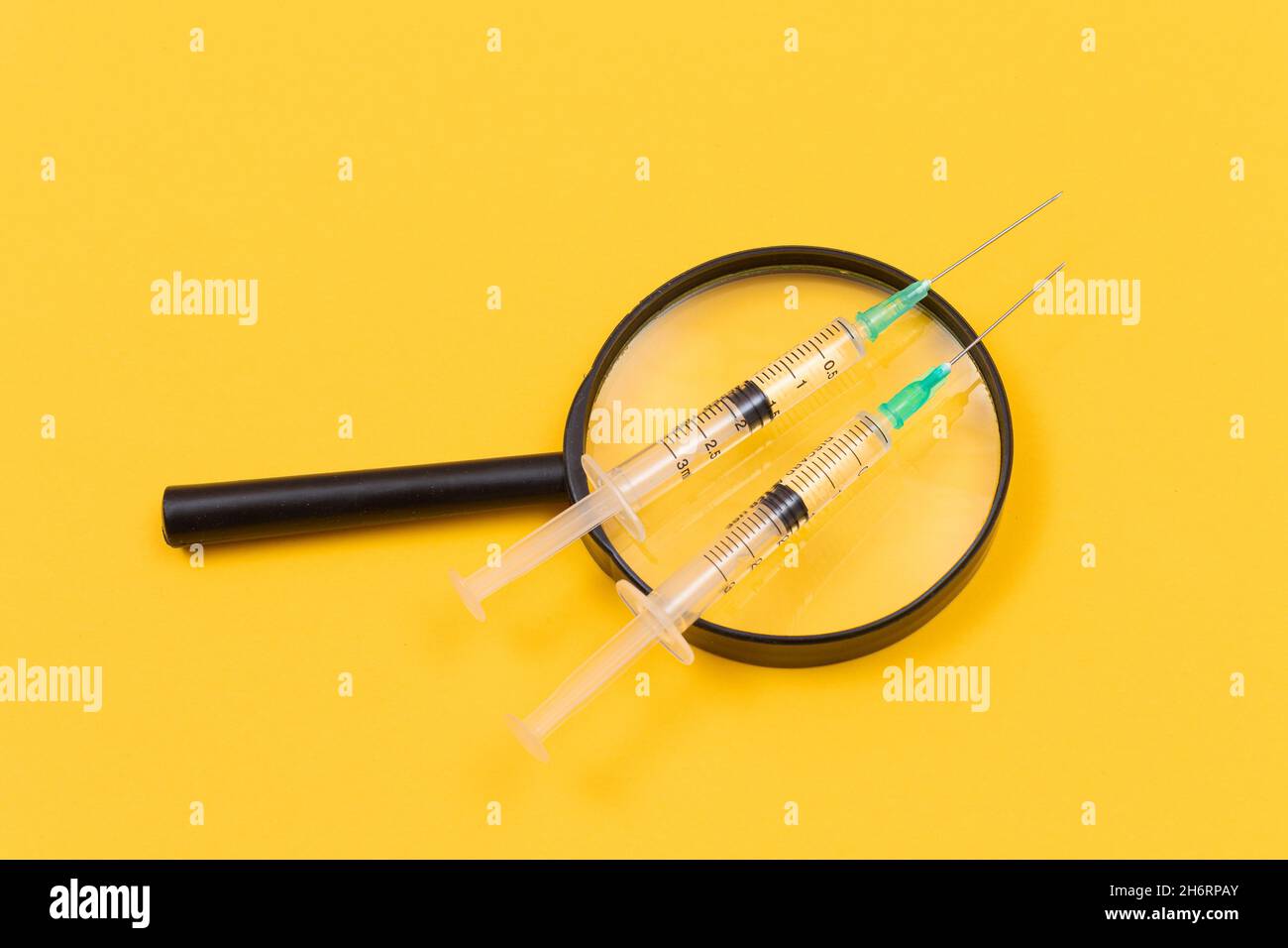 A Magnifier with Medical Syringe Lying on Yellow Table - Vaccination ...