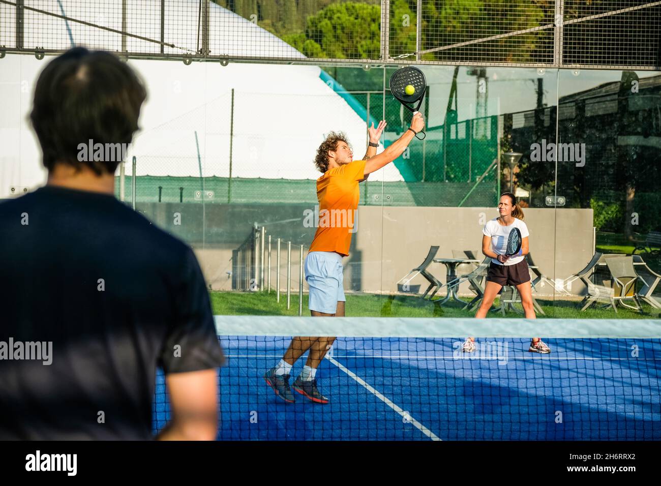 Mixed padel match in a blue grass padel court - Beautiful girl and ...