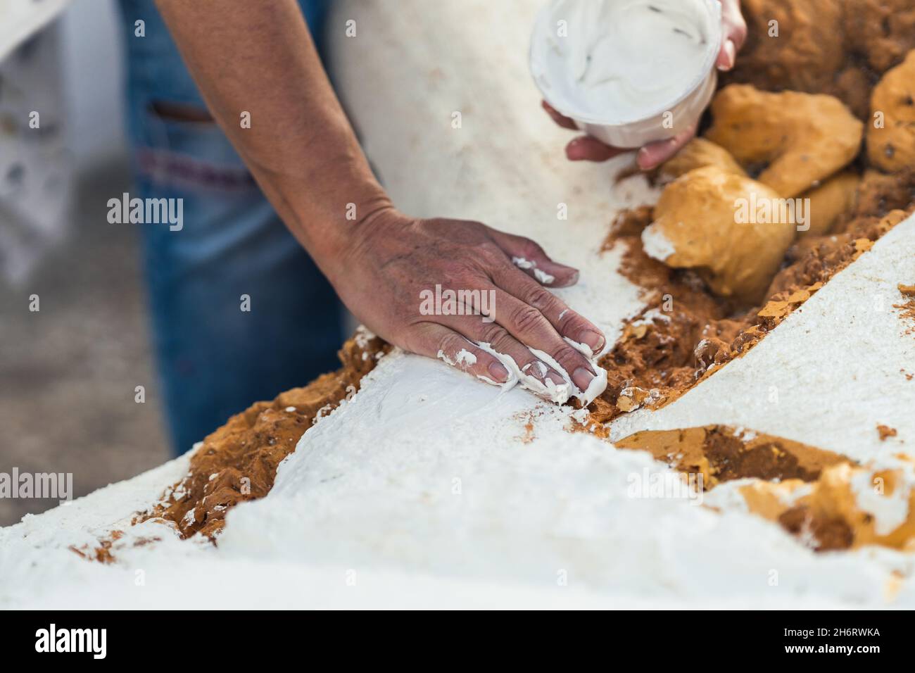 Female hand spreading white paste on the rough surface of a polystyrene ...