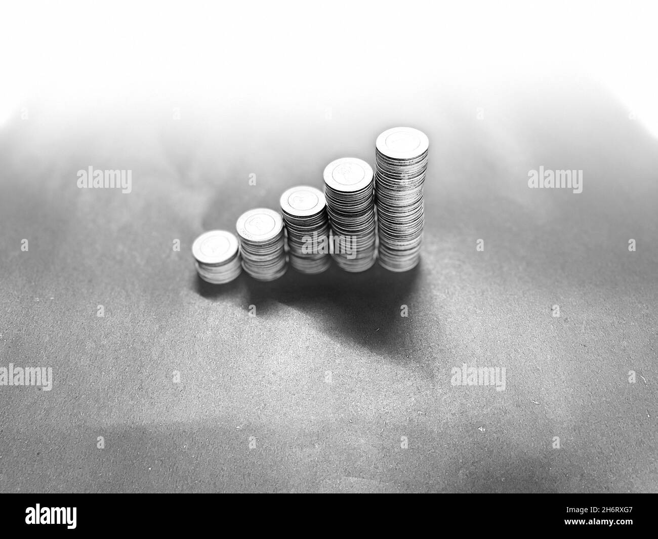 Grayscale shot of coins arranged to show financial growth on a black ...