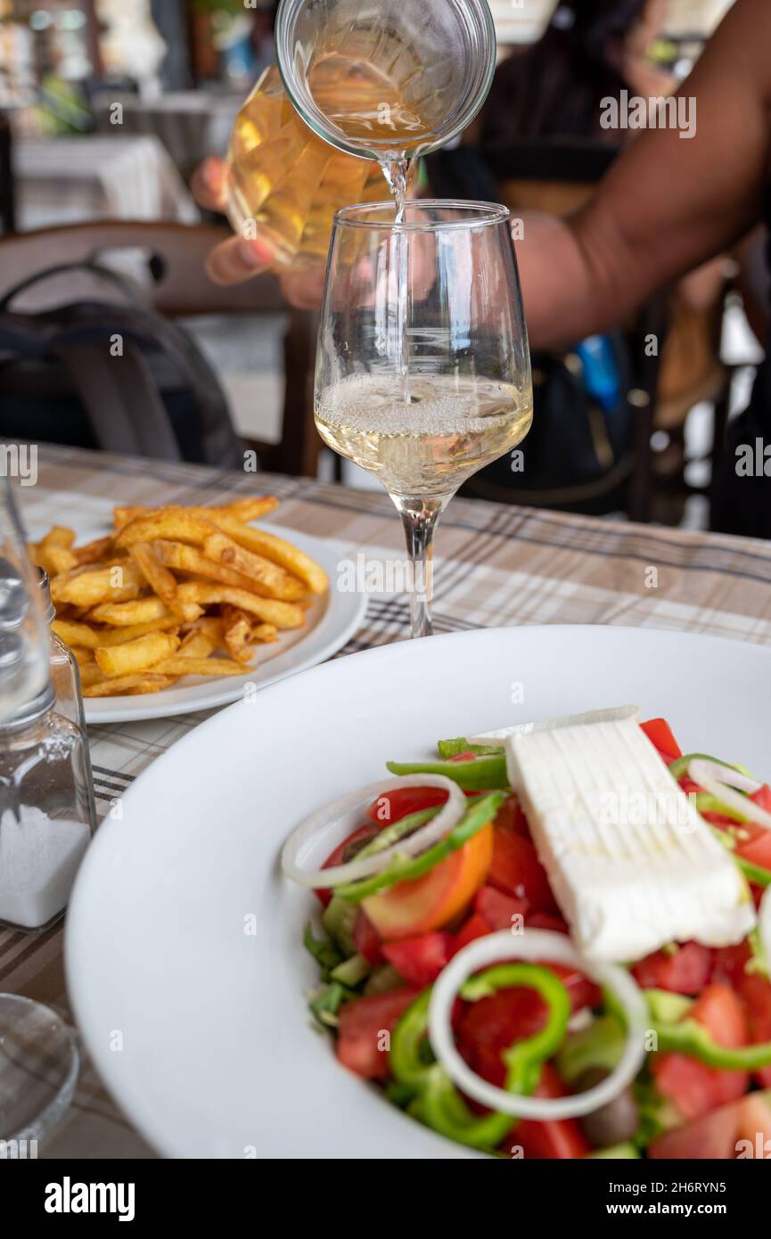 Dinner with white wine in Greek taverna, fresh vegetable greek salad ...