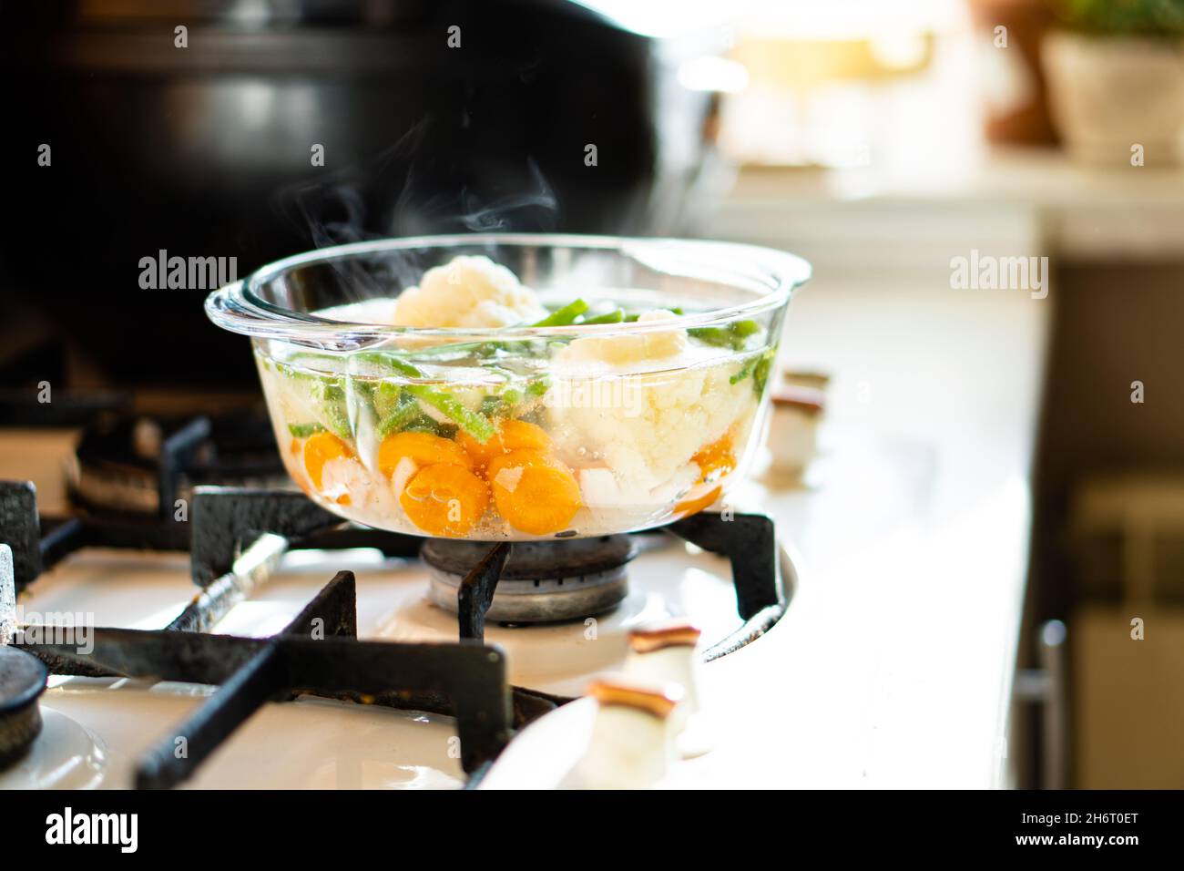 Transparent glass pan with vegetable soup, fresh hot food boils on the ...