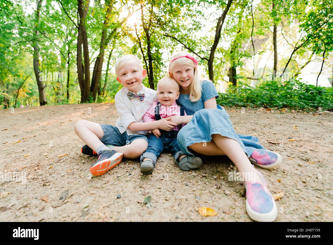 Straight on portrait of three siblings sitting together Stock Photo - Alamy