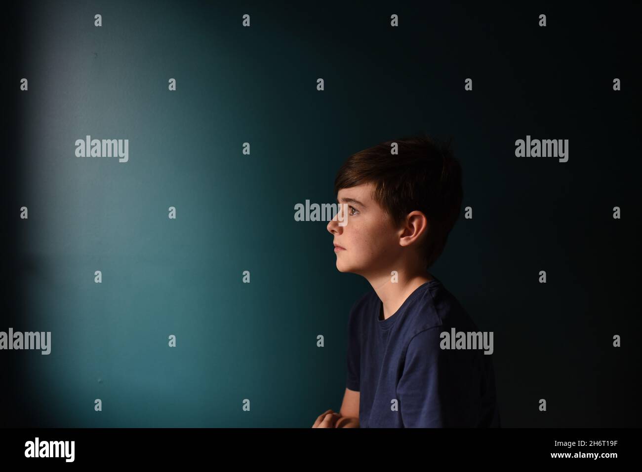 Portrait of a sad young boy against a dark blue wall Stock Photo - Alamy
