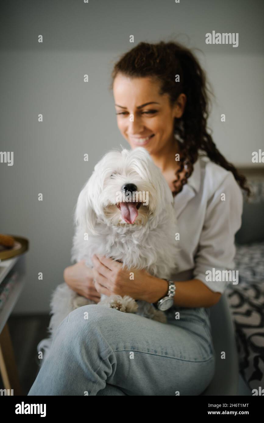 Woman sitting on a chair with a dog on her lap and smiling Stock Photo ...
