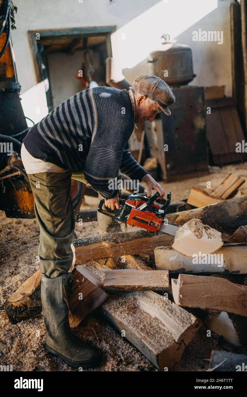 Old man cutting firewood at home Stock Photo - Alamy