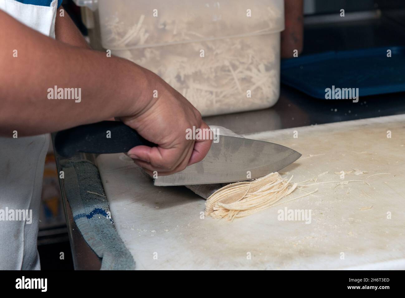 Skilled hands of the sous chef slices thin the tortilla strips to be ...
