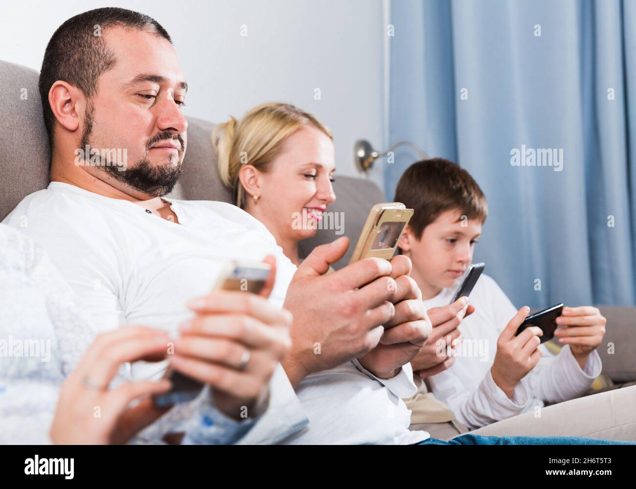 Parents and son using phones at home Stock Photo - Alamy
