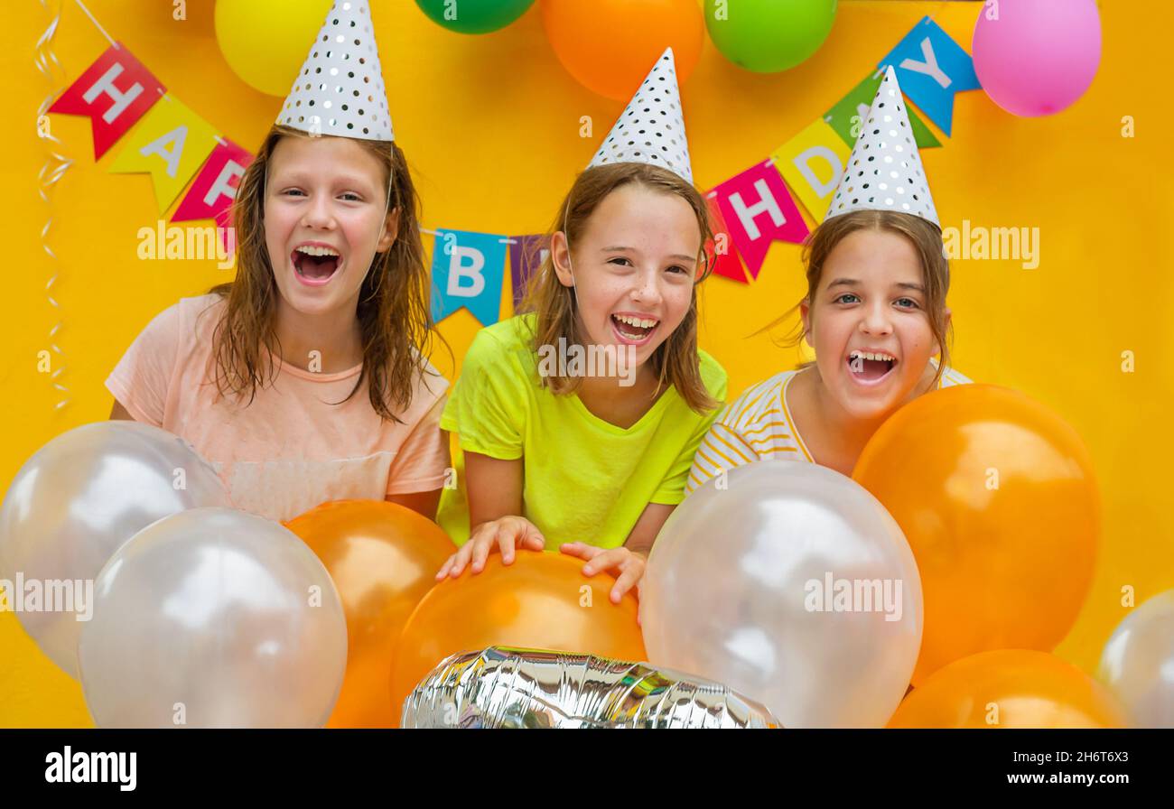 Three girls with balls on a yellow background. Children at the birthday ...