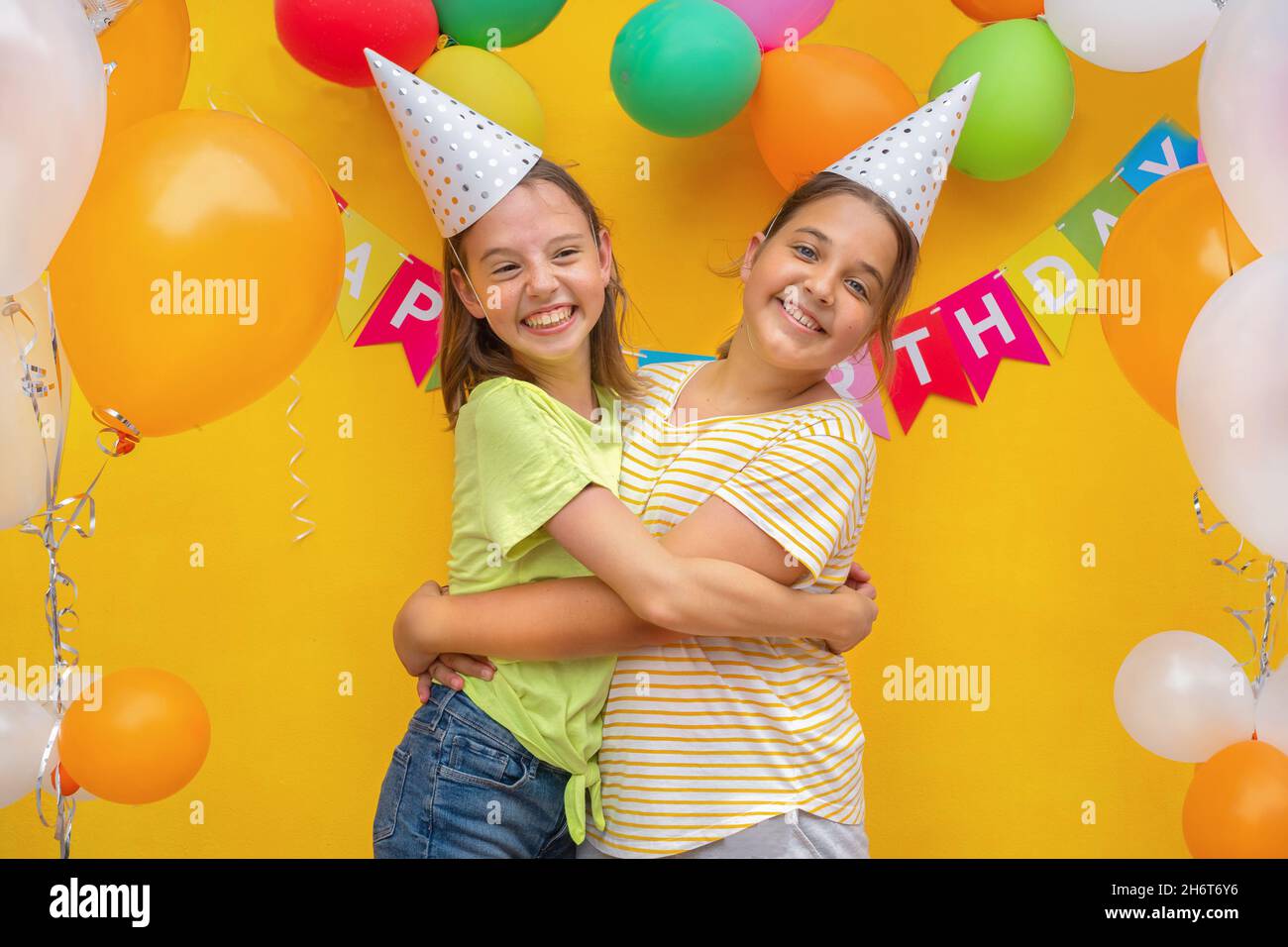 Two girls with balls hugging on a yellow background on a holiday Stock ...