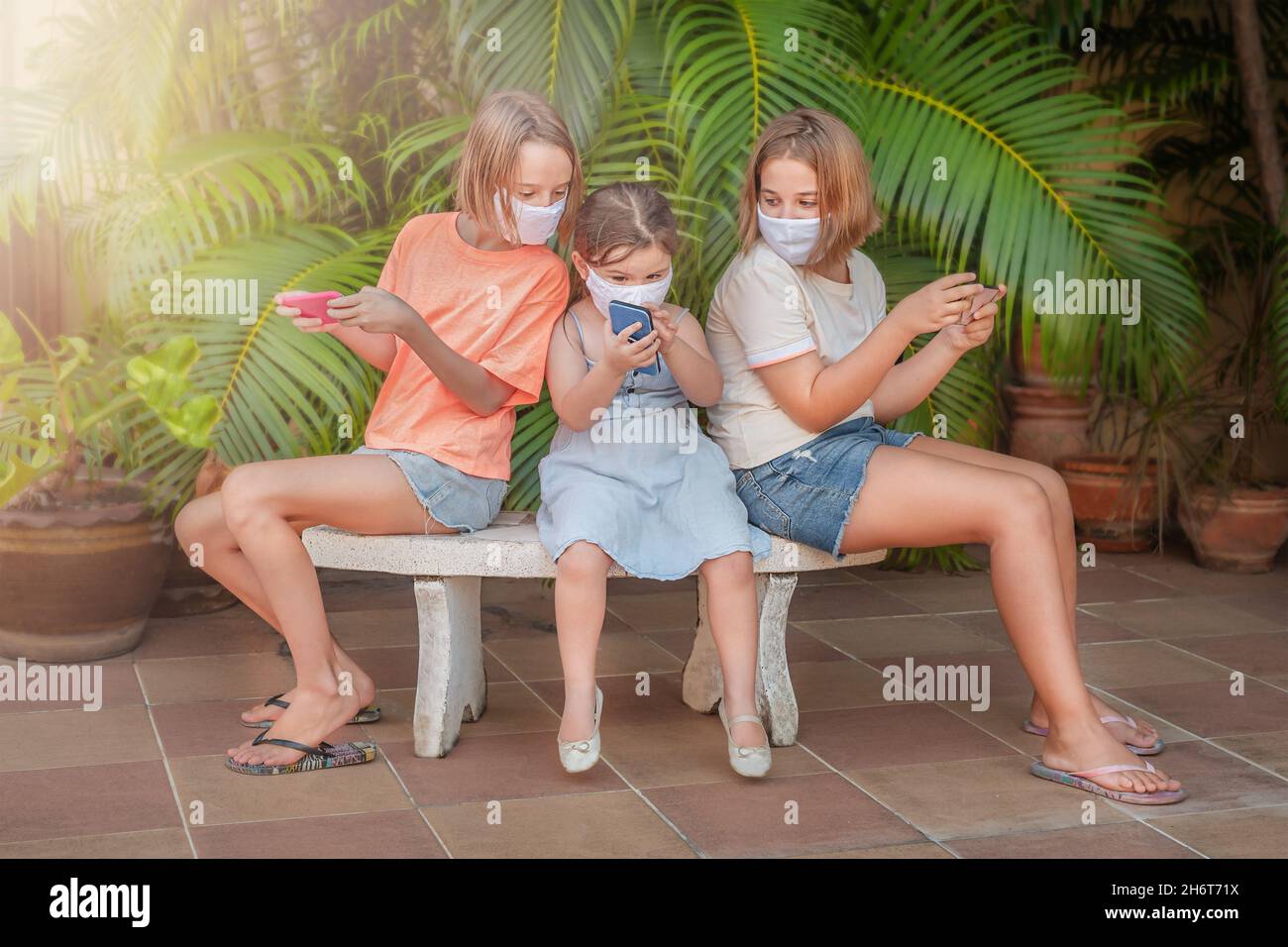 Children play gadgets on the bench. Girls spend time together Stock ...