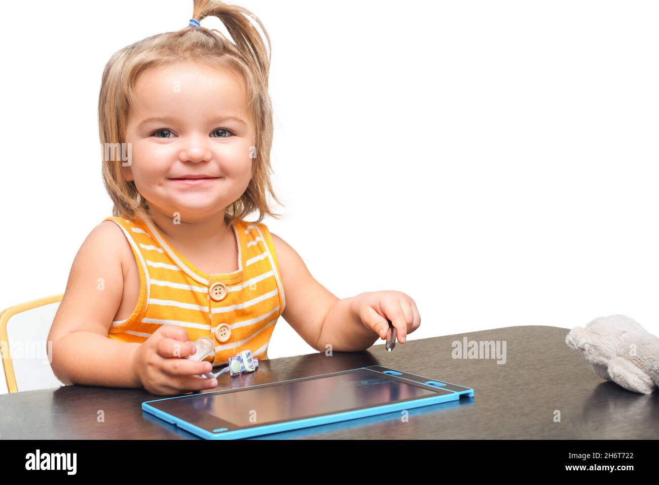 Portrait of child at table with graphic tablet toy isolated on white ...