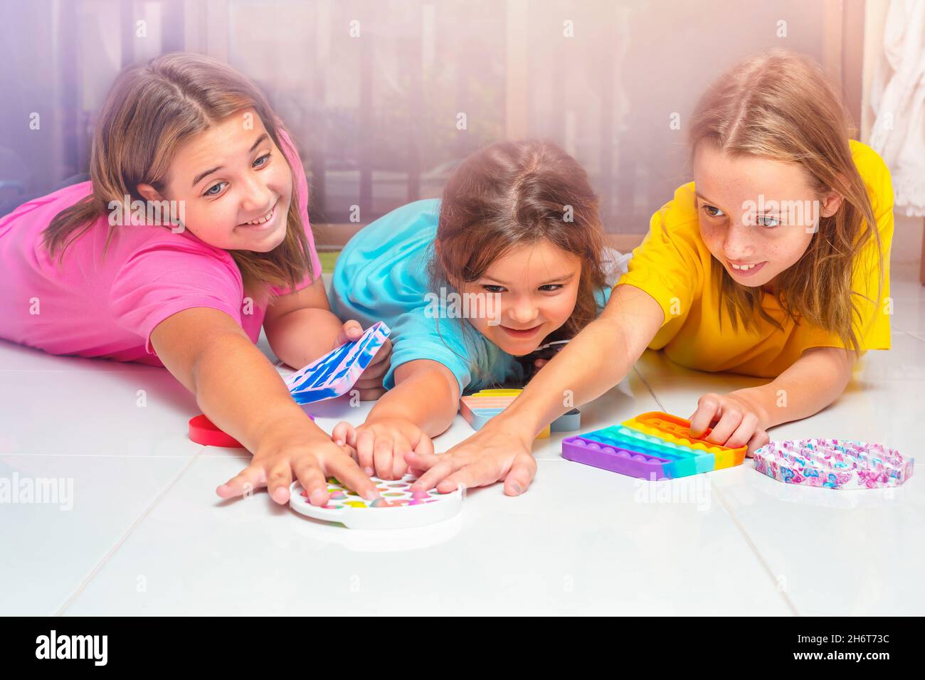 Girls friends reach out together for one toy lying on the floor Stock ...