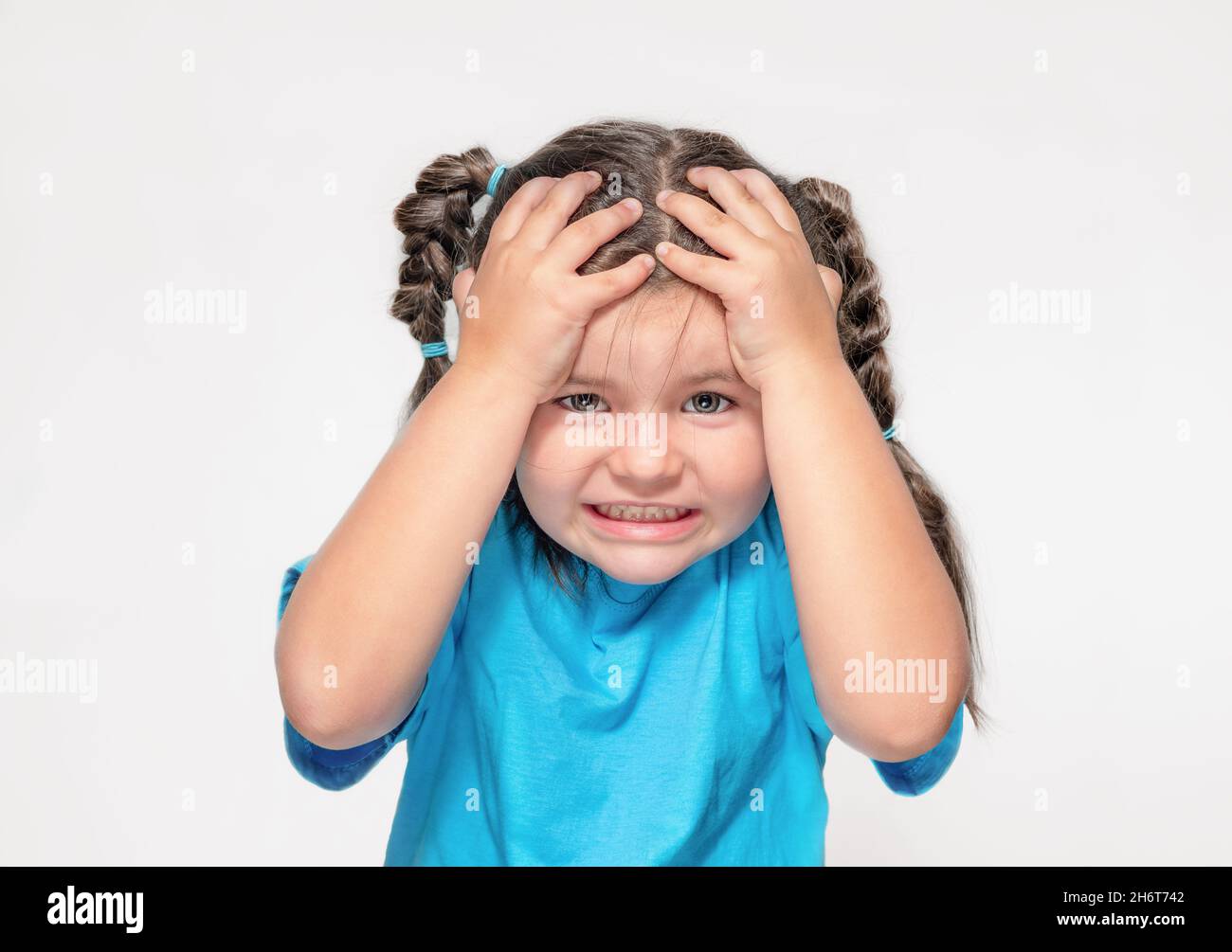 Child holding hands behind head with upset facial expression on gray ...