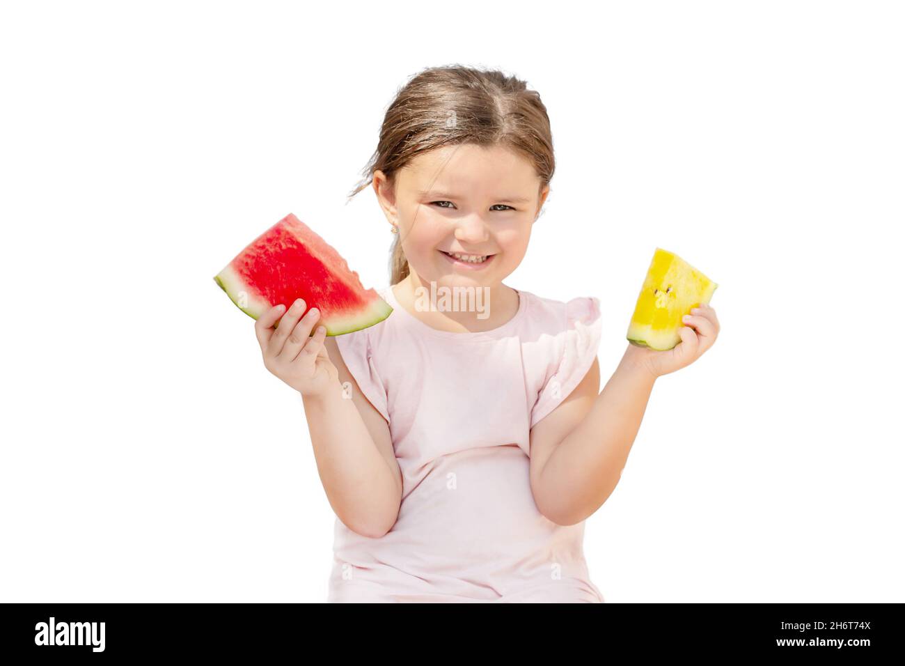The child is holding pieces of watermelon. The girl smiles and makes a ...