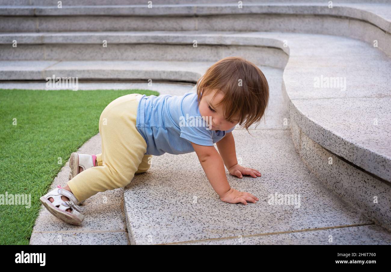 The baby crawls up the concrete stairs and looks around Stock Photo - Alamy