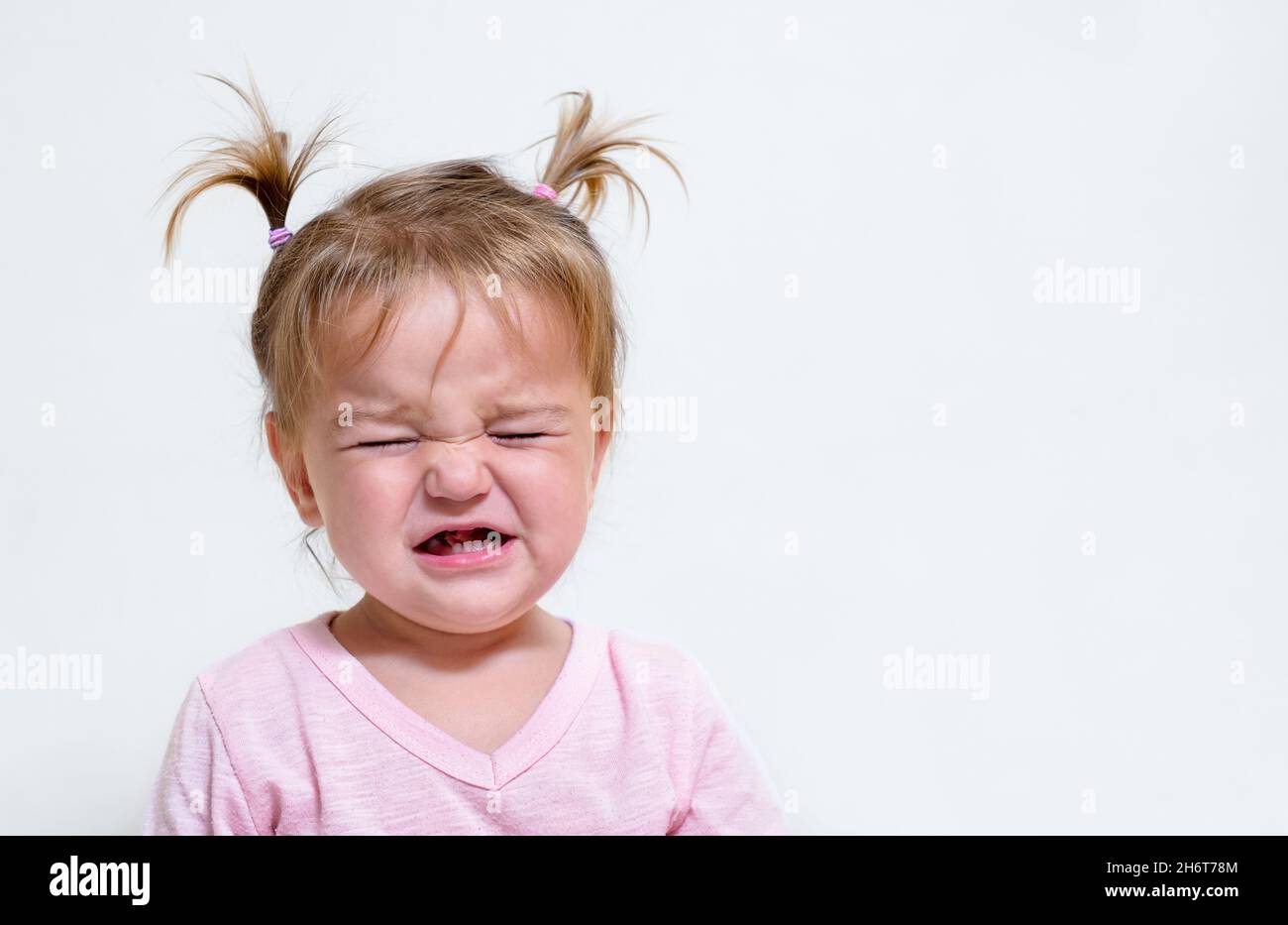 Portrait of an upset child. Girl crying on the background of the wall ...