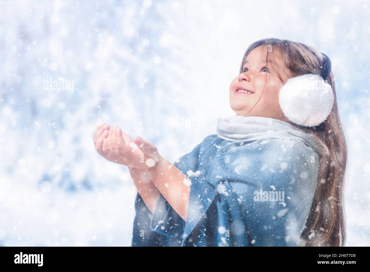 Child girl walks in the winter forest and catches snowflakes Stock ...