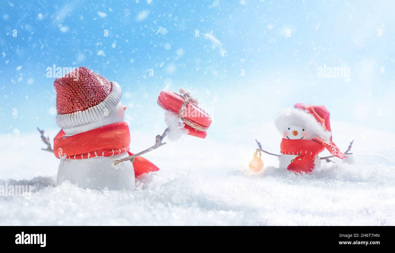 Snowman hands out a gift to the second snowman with a flashlight on a ...